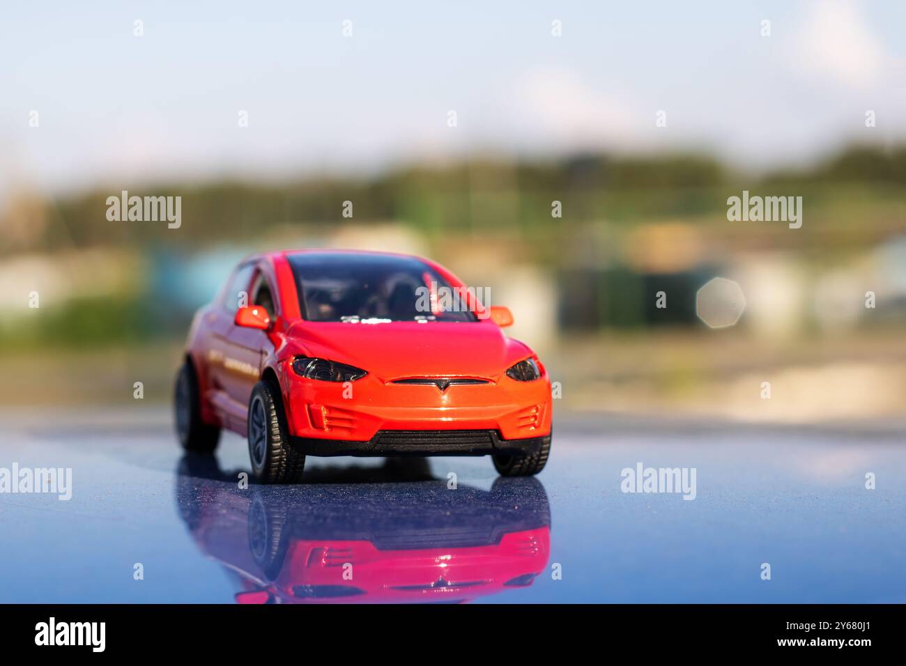 A bright red toy car is parked on a smooth, vibrant blue surface ...
