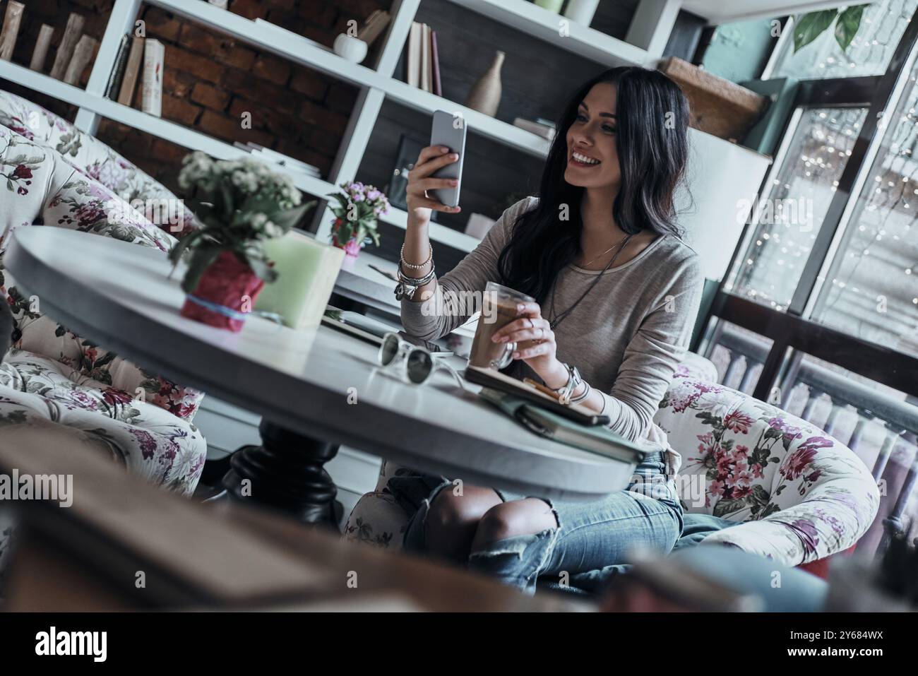 Receiving nice messages. Attractive young smiling woman using her smart ...