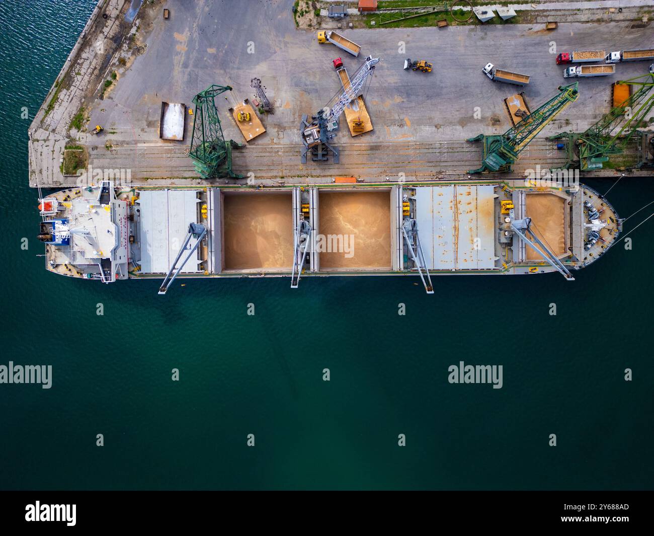 Aerial view of a cargo ship in a harbor uploading grains in a busy port ...