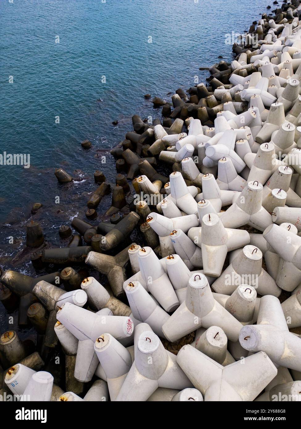 Heavy concrete tetrapods lined along the shoreline at a coastal area ...