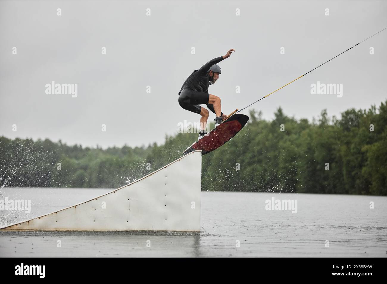 Side view action shot of male sportsman wakeboarding and doing trick ...