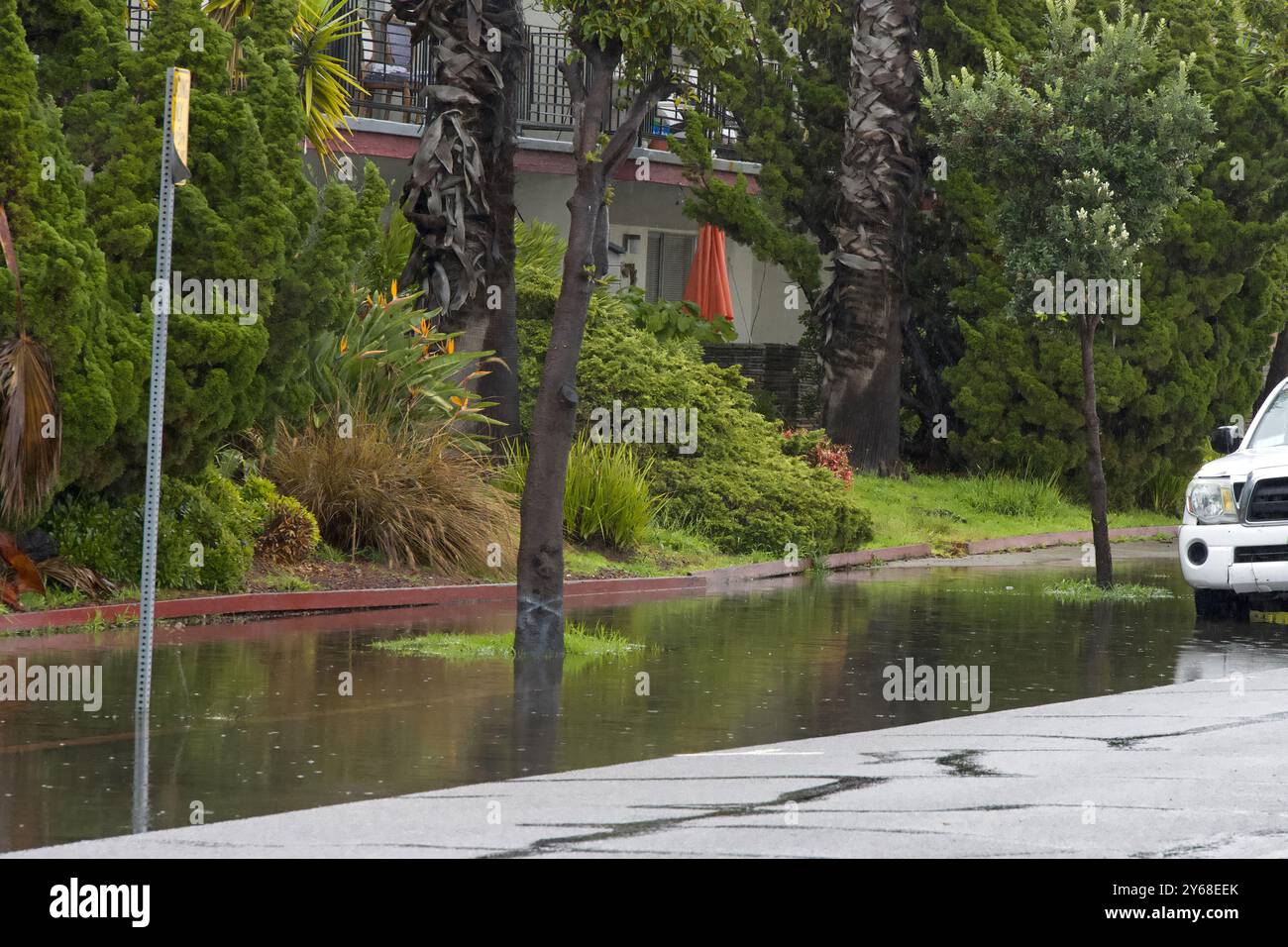 Sidewalk and side of road with standing water, flooded after heavy rain ...