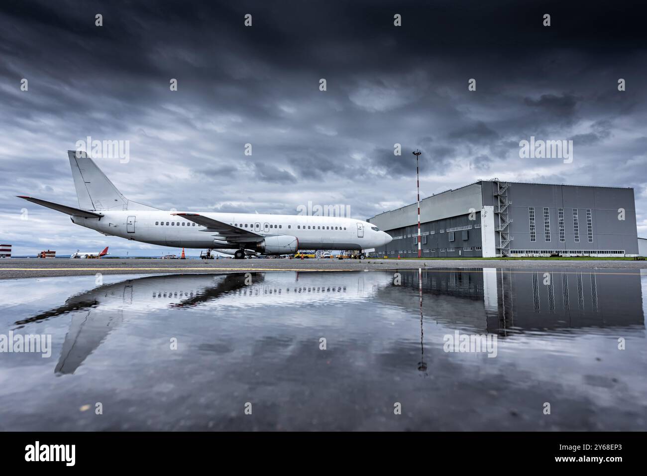 White passenger airplane at airport near aircraft hangar with ...