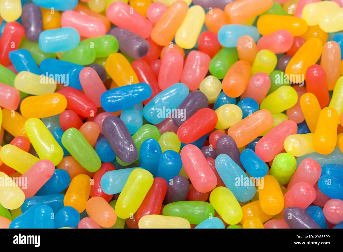 Many brightly colored jelly beans in a rainbow of pastel colors ...
