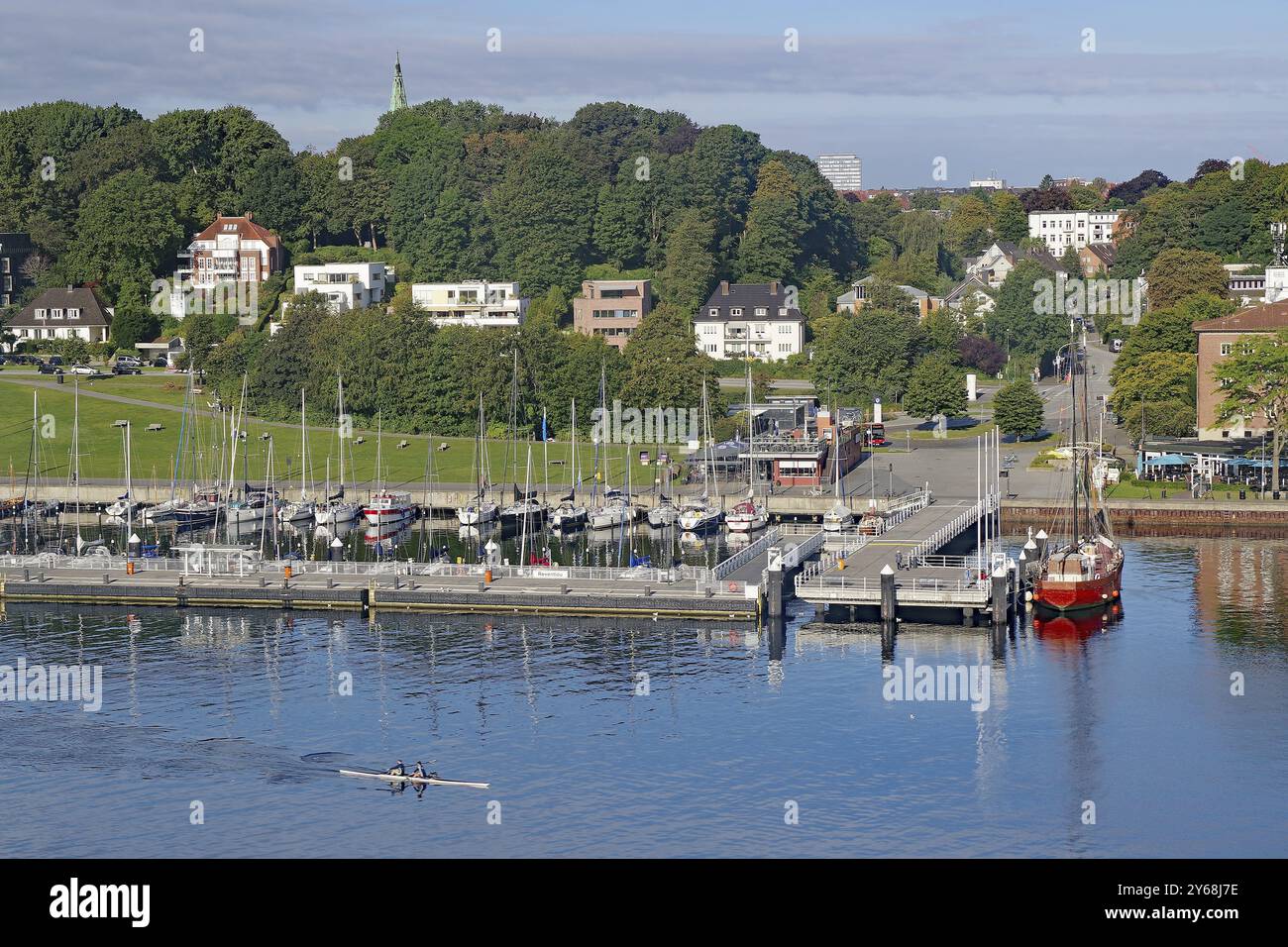 Small harbour with boats, surrounded by residential buildings and green ...