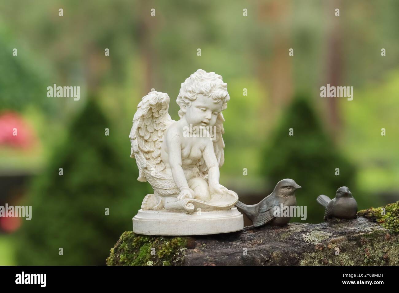 Small white angel statue and two birds placed on a tombstone. Old ...