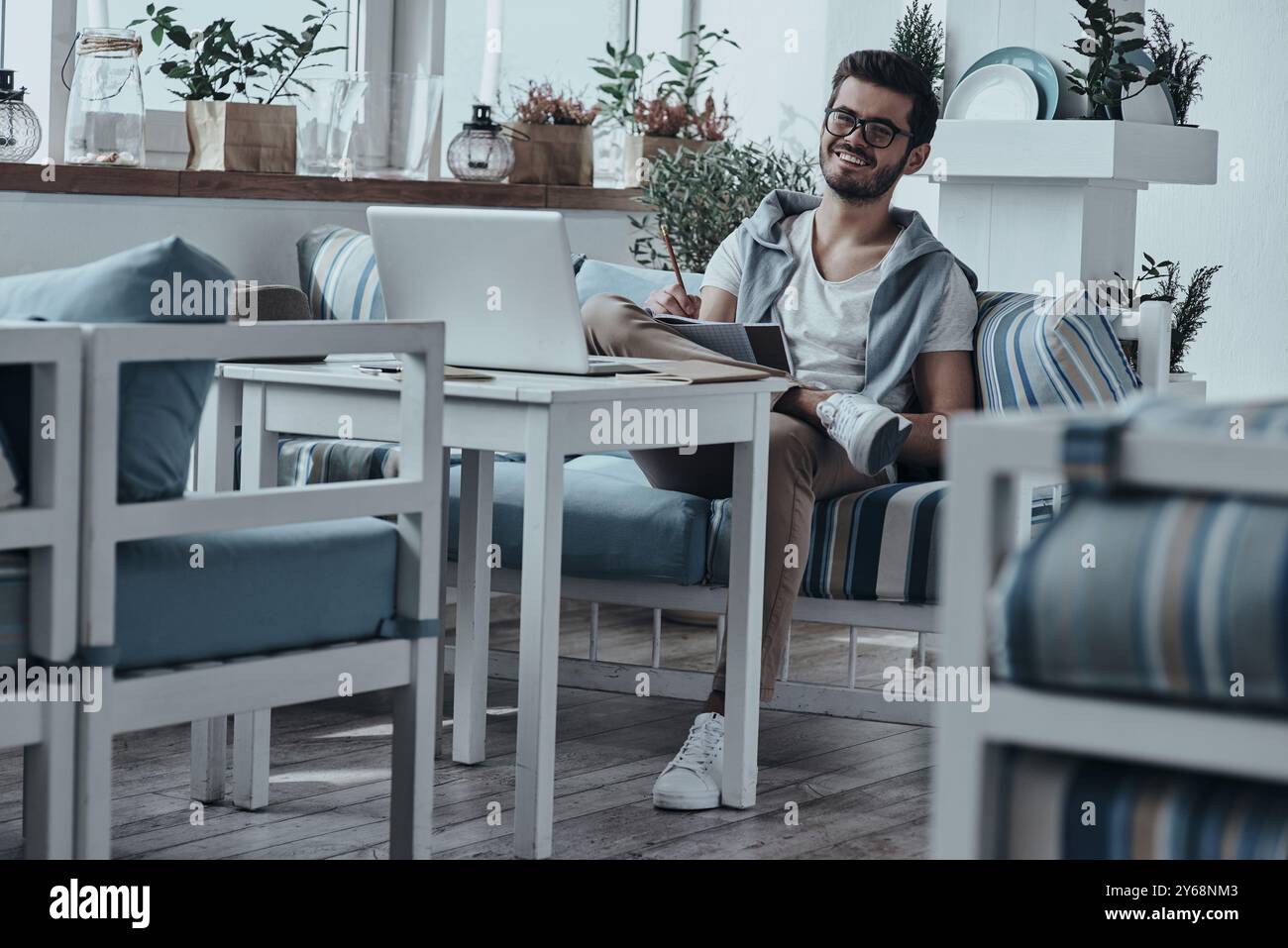 Enyoing nice day. Good looking young modern man writing something down ...
