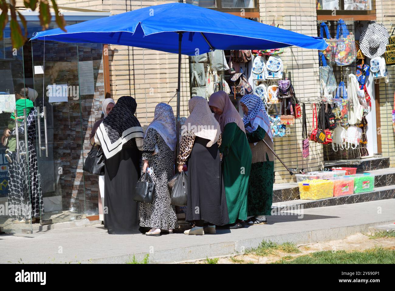 Local women in traditional dress buy sweets on the streets of the city ...