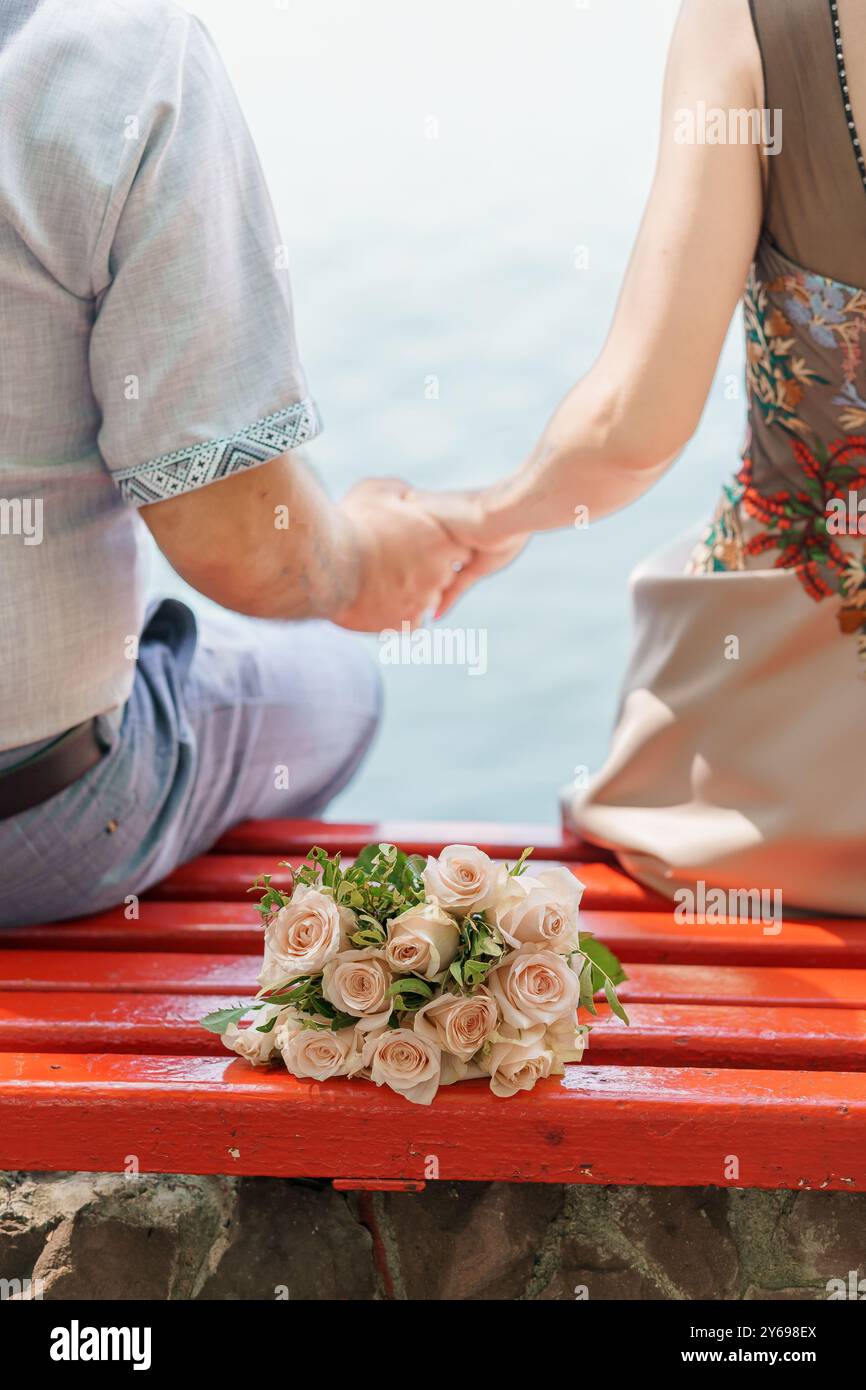 Romantic Couple Holding Hands by Serene Waters with a Beautiful Rose ...