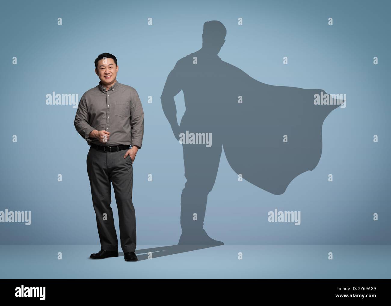 Confident businessman casting shadow of superhero on light blue ...