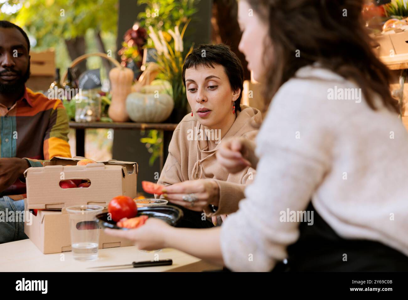 Female vendor sitting with multicultural couple, giving fresh fruits ...