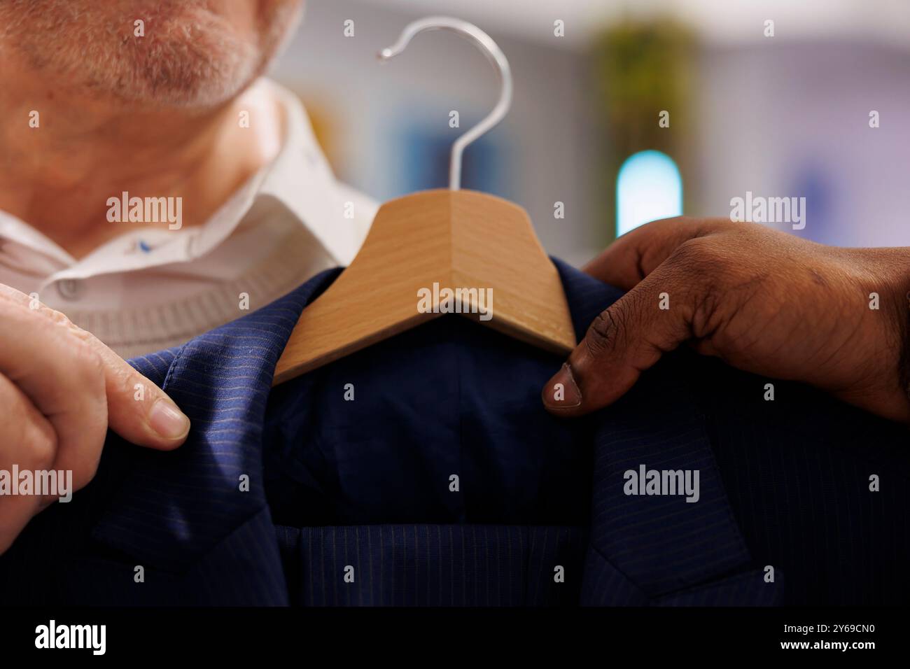 Employee showing blazer to customer in clothing store, presenting new ...