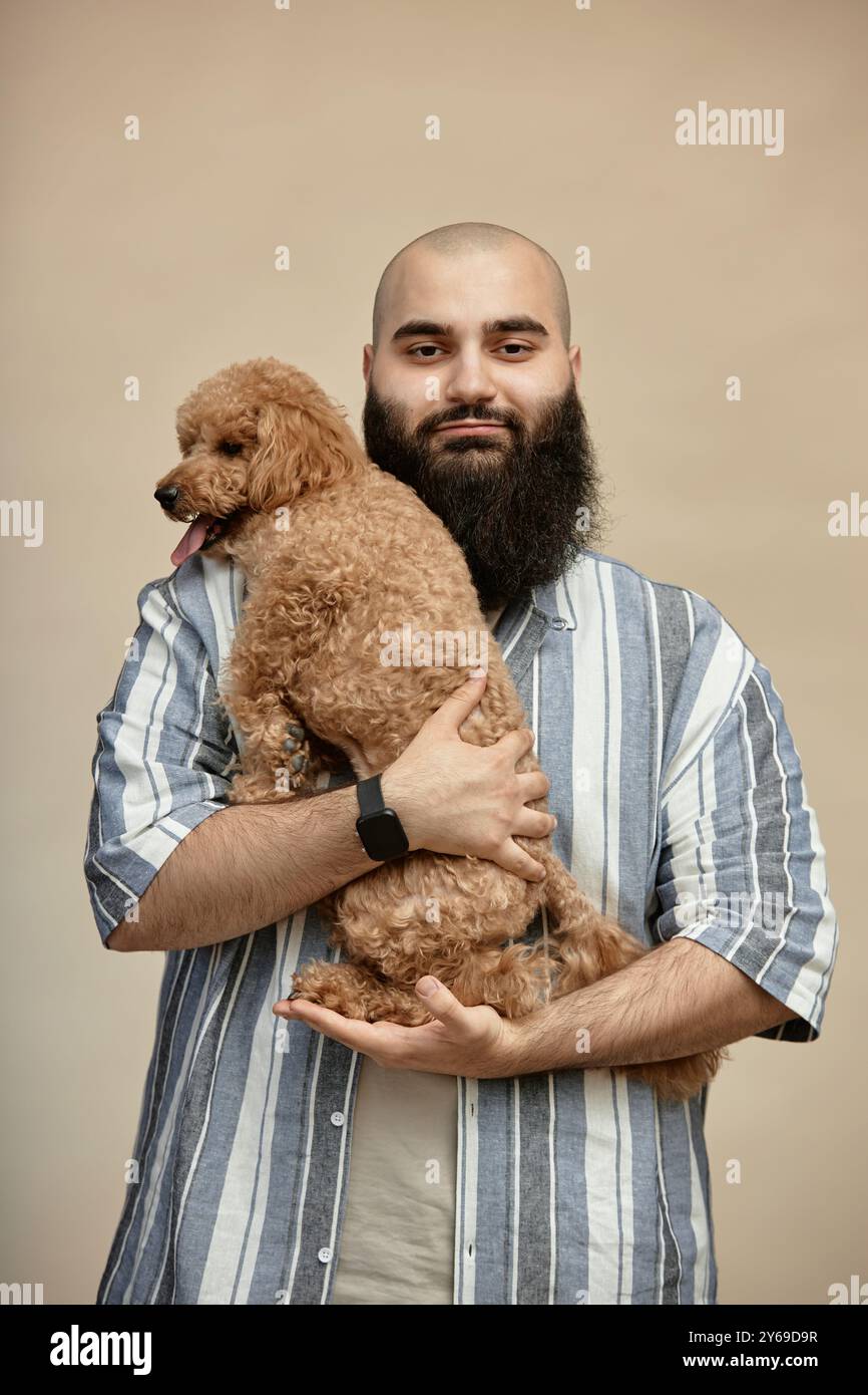 Portrait of bearded man with small brown dog in his hands both looking ...