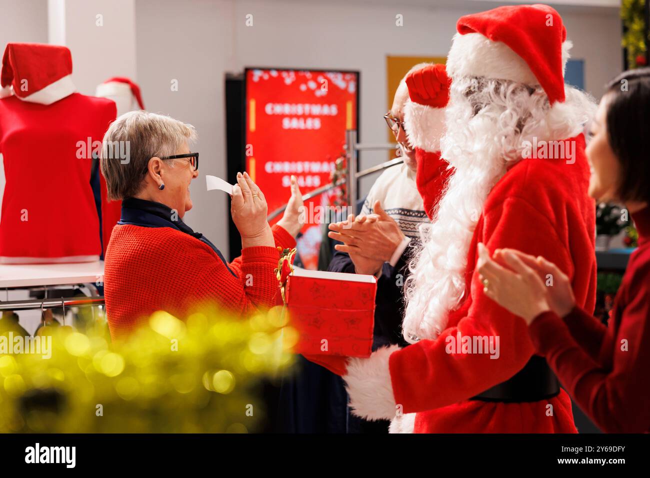 Elderly adult winning raffle prize in retail store, feeling happy about ...