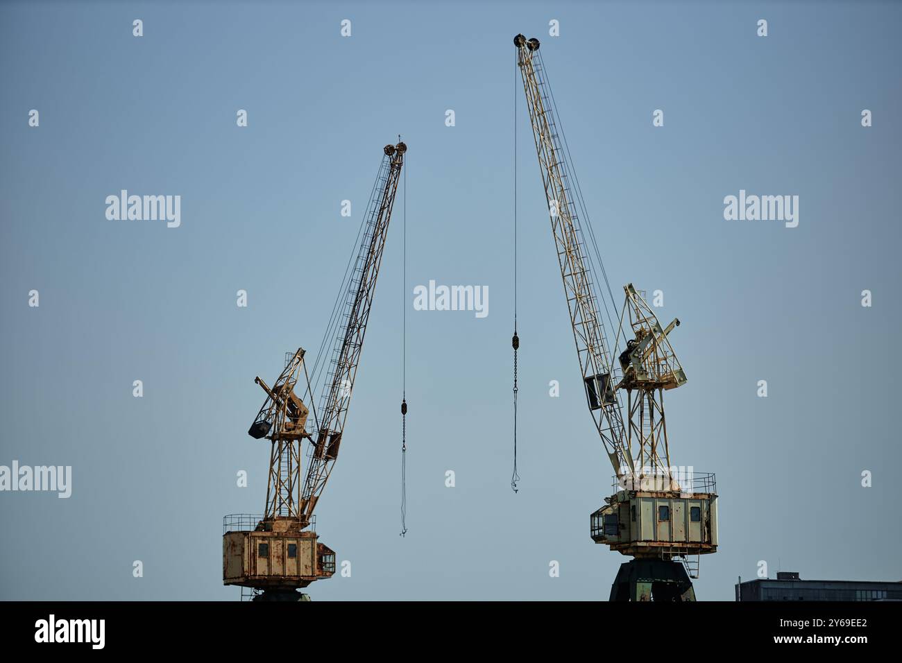Dual cranes standing tall against clear sky forming prominent vertical ...