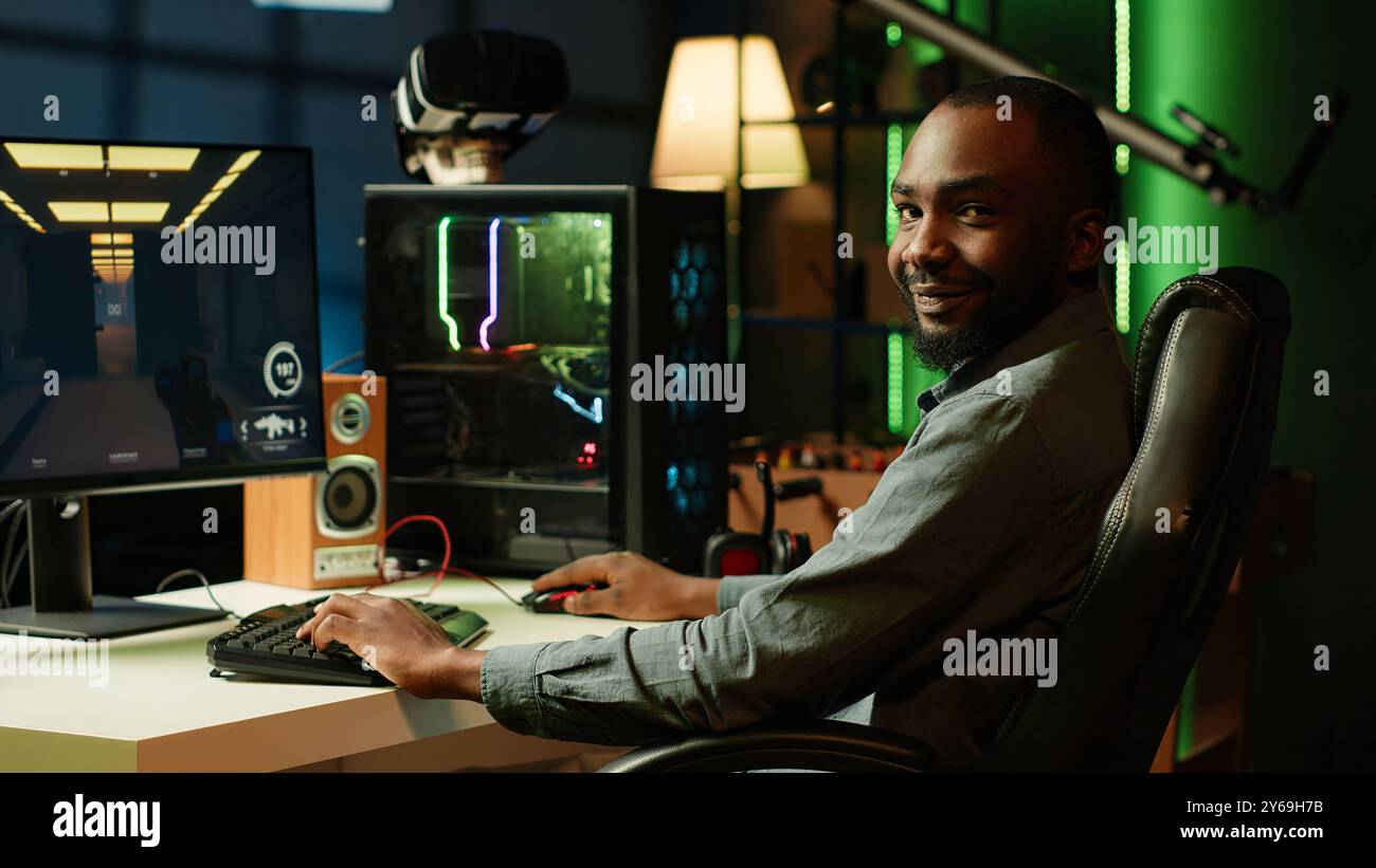 Portrait of smiling man playing FPS videogame on PC screen in neon ...
