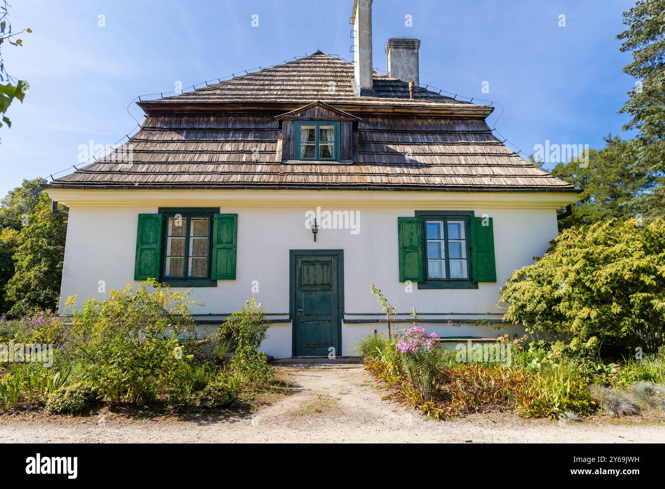 A traditional countryside house with a wooden roof and green shutters ...