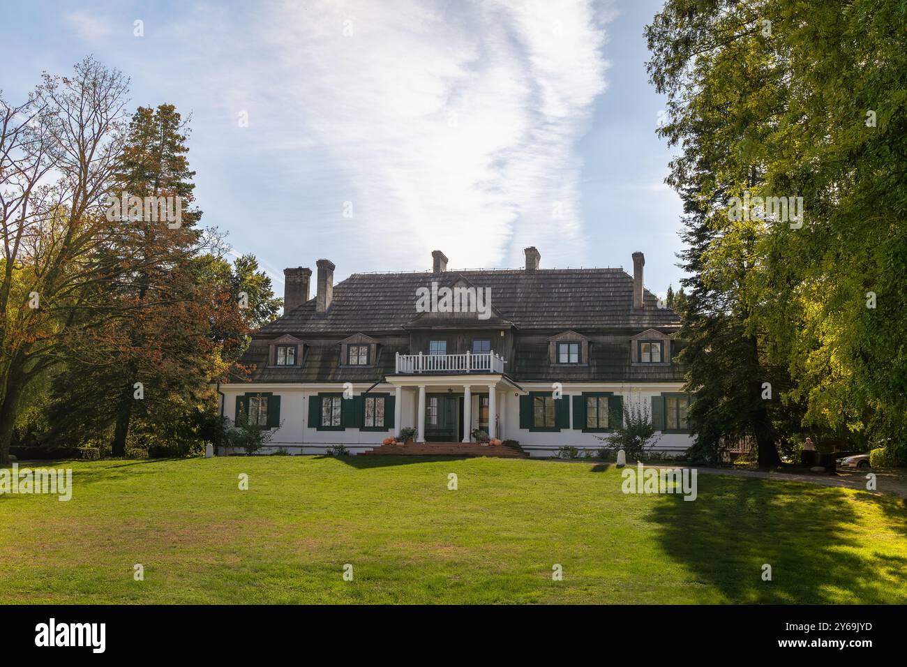 Historic manor house with a large green lawn and surrounding trees ...