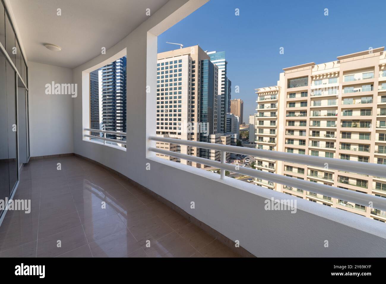 spacious balcony in Dubai. It has a white balustrade, tiled floor, and an unobstructed view of ...