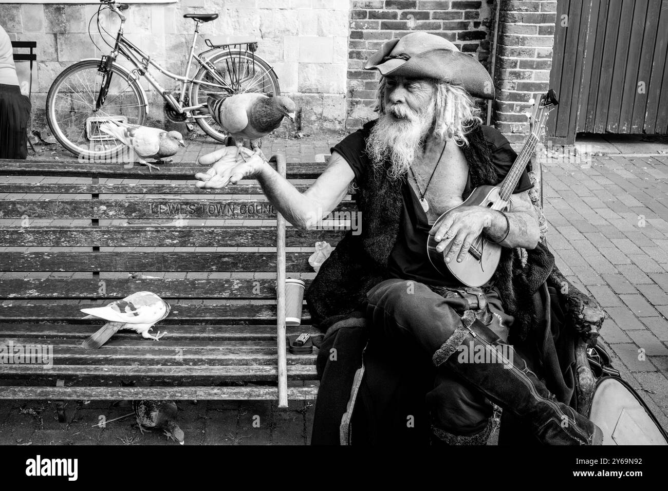 A Street Entertainer In A Pirate Costume Sits On A Public Bench Feeding ...