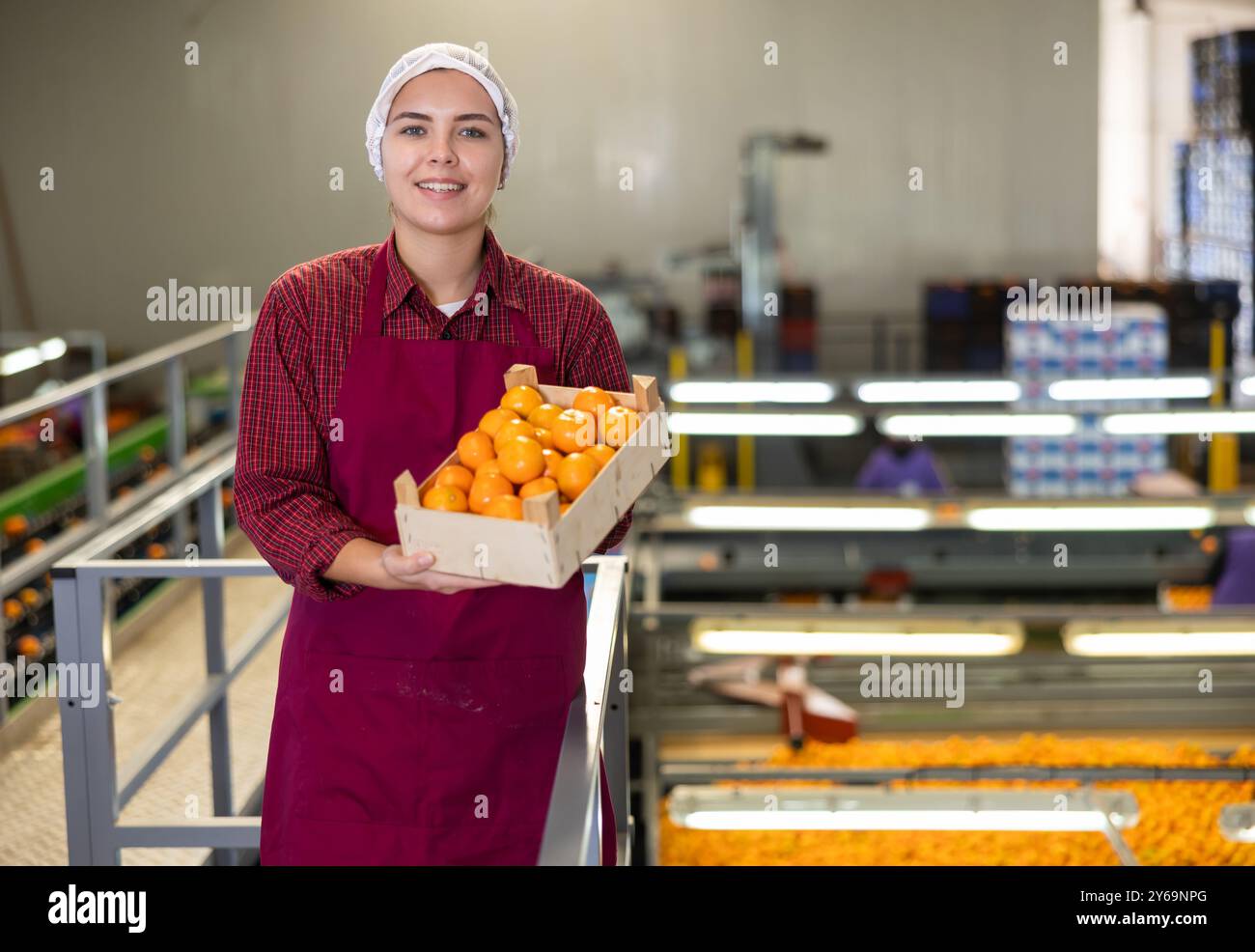 Happy female sorting factory worker showing mandarins in box Stock ...