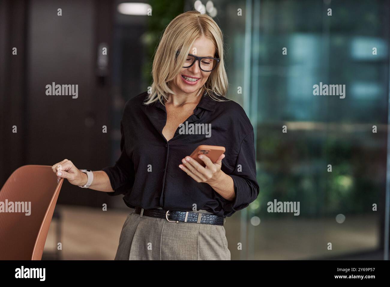 A professional woman in her office uses a smartphone to stay connected ...