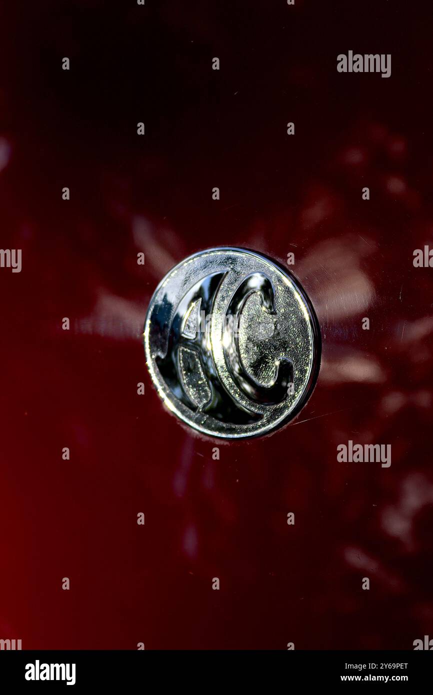 Chrome AC car badge on an AC Ace sports car, with dappled sunlight ...