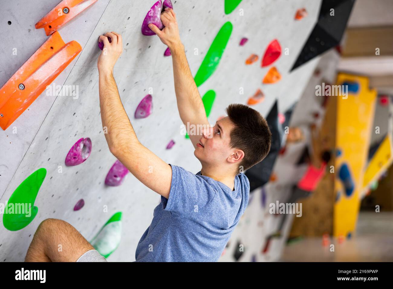 Male mountaineer climbing artificial rock wall without his belay ...