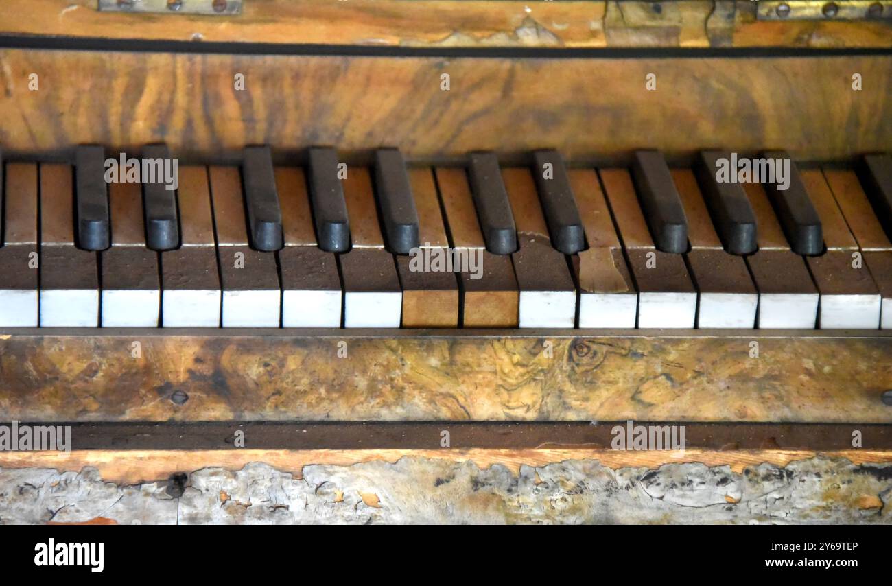 Old saloon piano has missing ivory from keys. Closeup shows piano keys ...