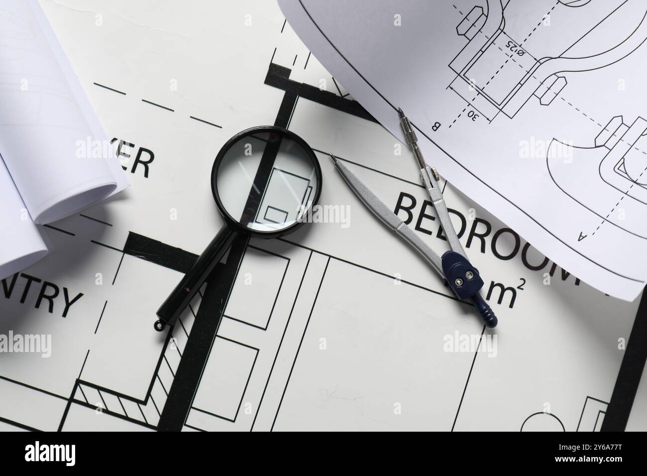 Dividers and magnifying glass on different engineering drawings, top ...