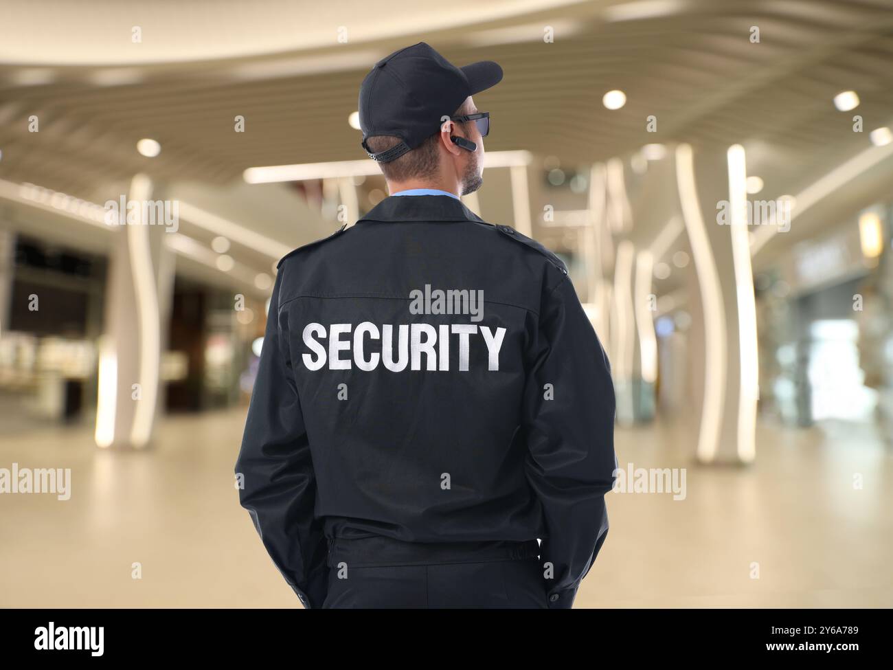 Security guard in uniform and earpiece in shopping mall, back view ...