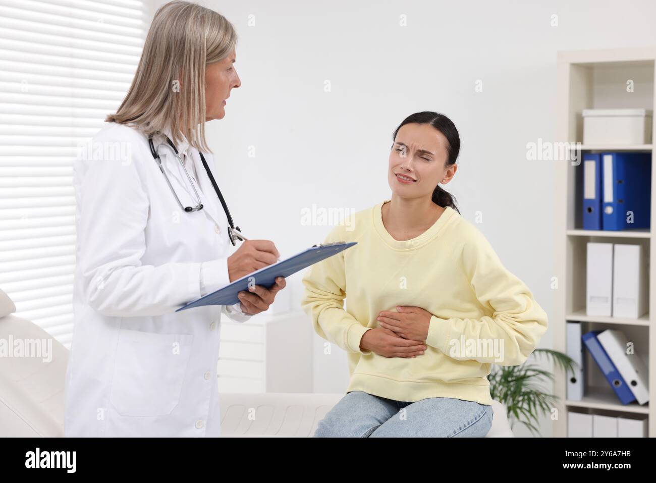Senior doctor consulting patient with stomach pain in hospital Stock ...