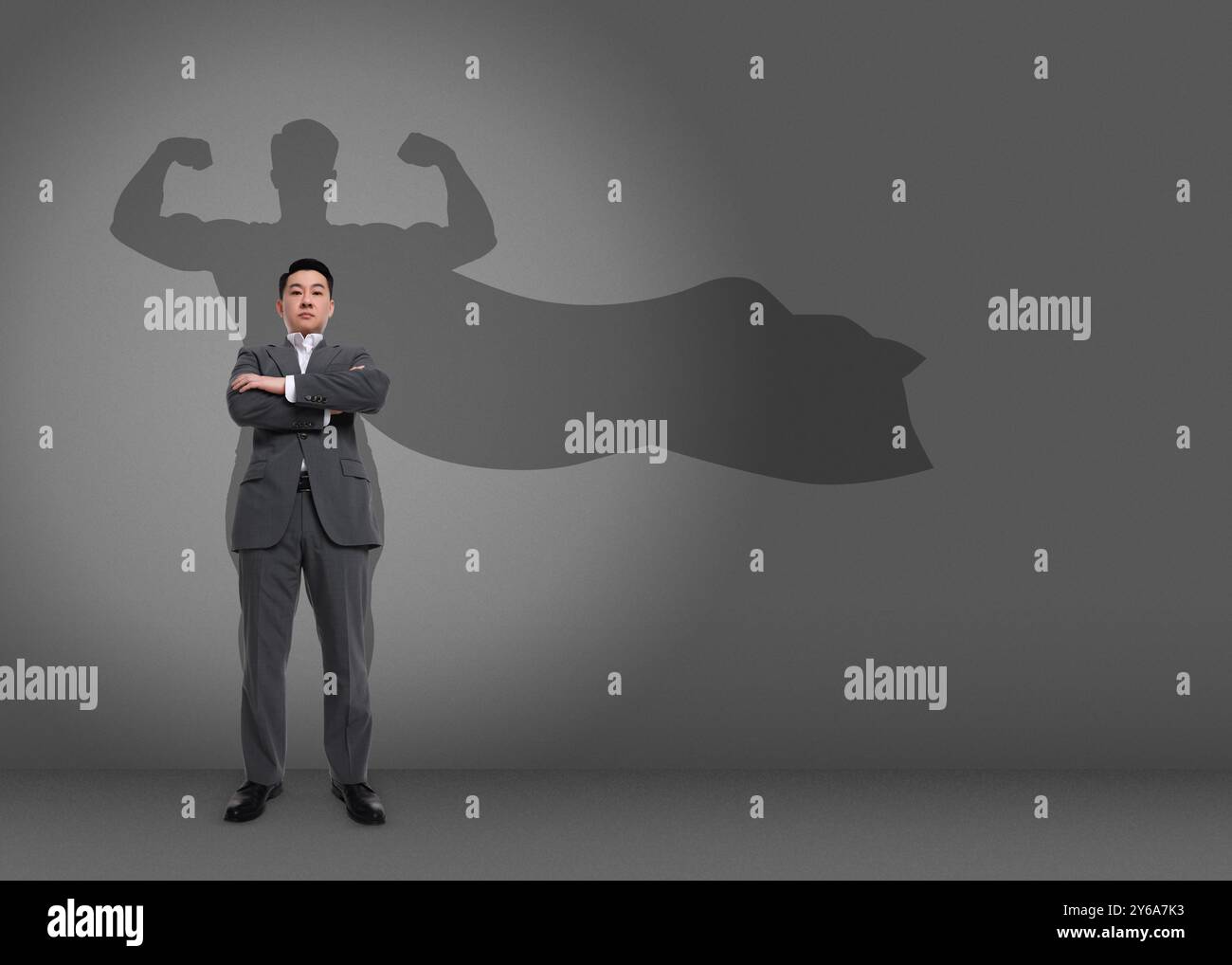 Confident businessman casting shadow of superhero on grey background ...