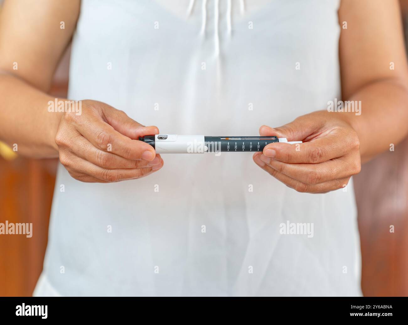 Women turn knob on end of insulin pen and dial up correct insulin dose ...