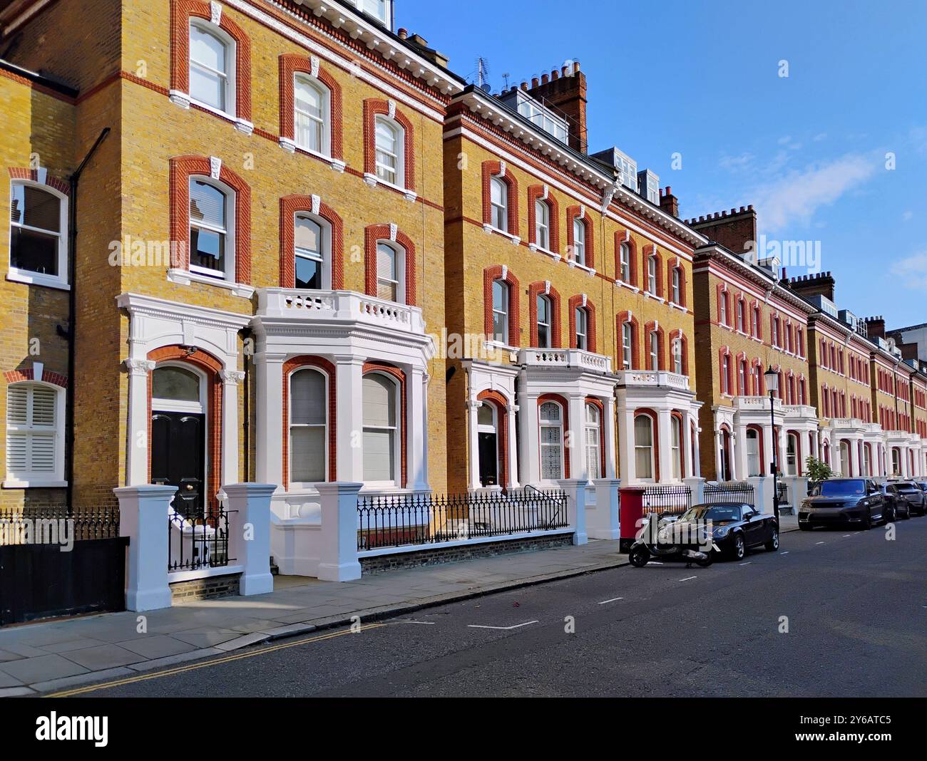 Street of yellow brick townhouses with red trim around windows Stock ...