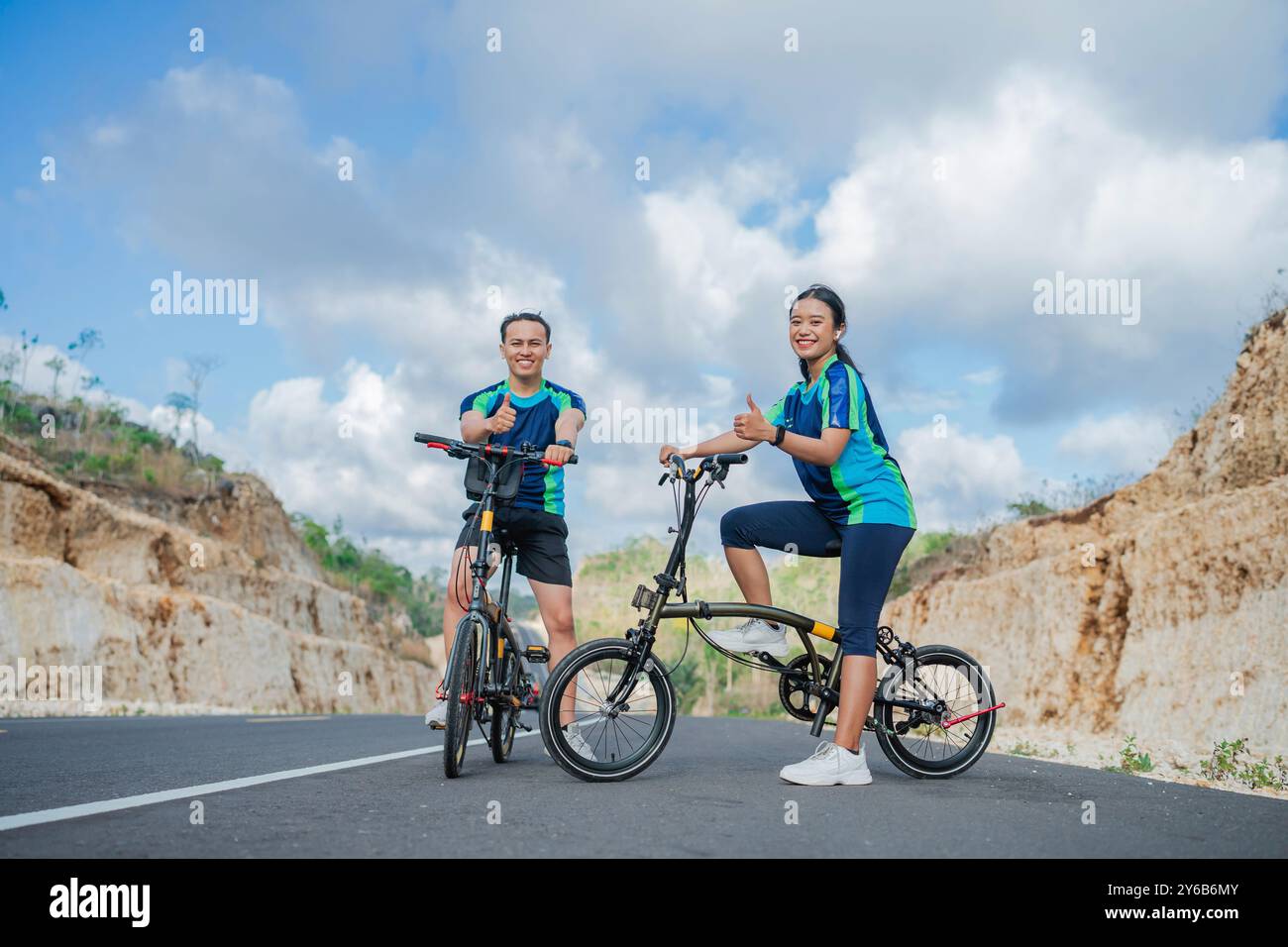 male and female biker riding bike thumb up Stock Photo - Alamy