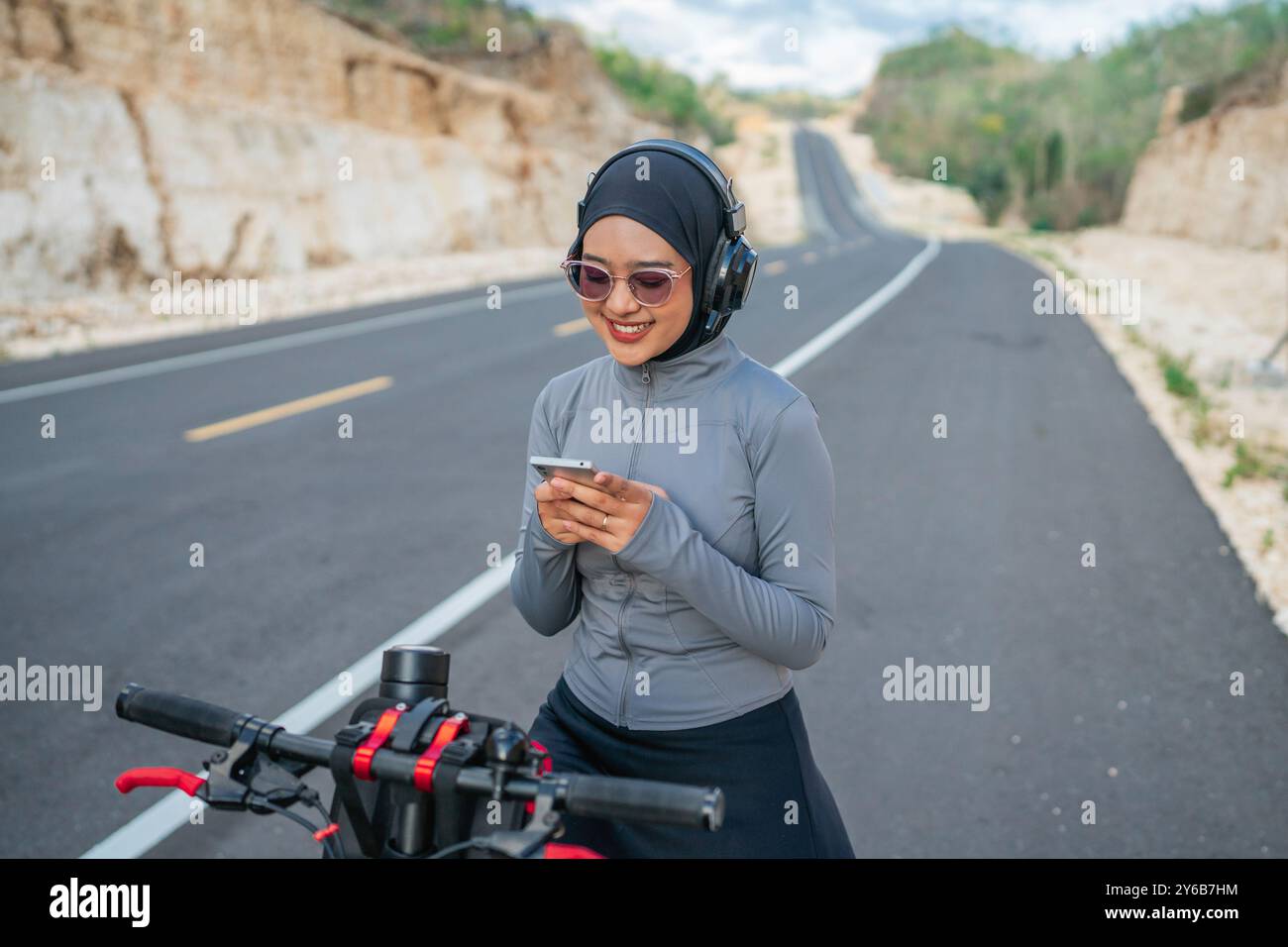 hijab biker using phone when riding bike Stock Photo - Alamy
