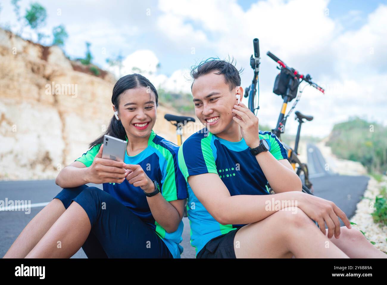 female and male biker using phone sharing earphone Stock Photo - Alamy