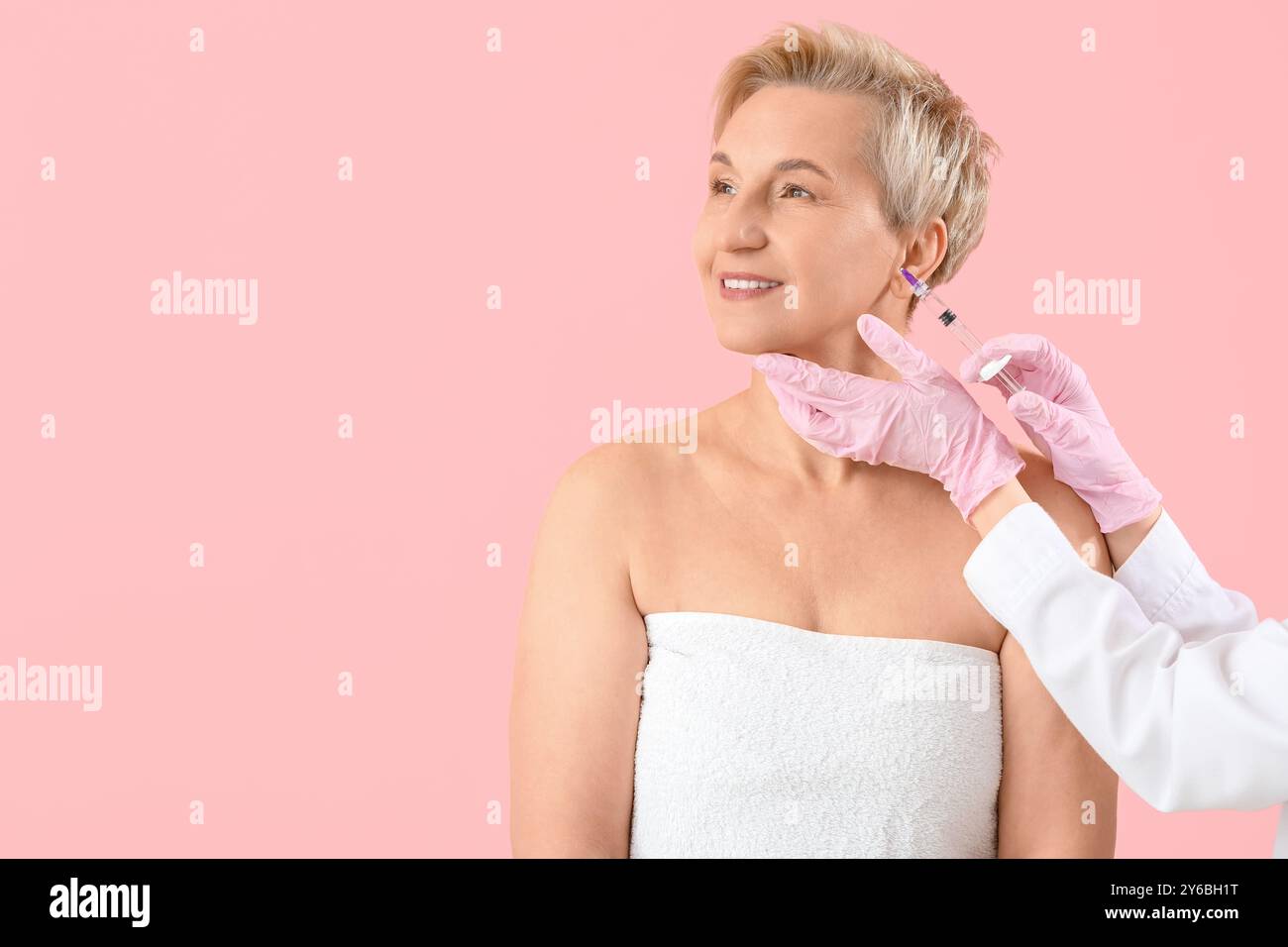 Mature woman receiving filler injection on pink background Stock Photo ...