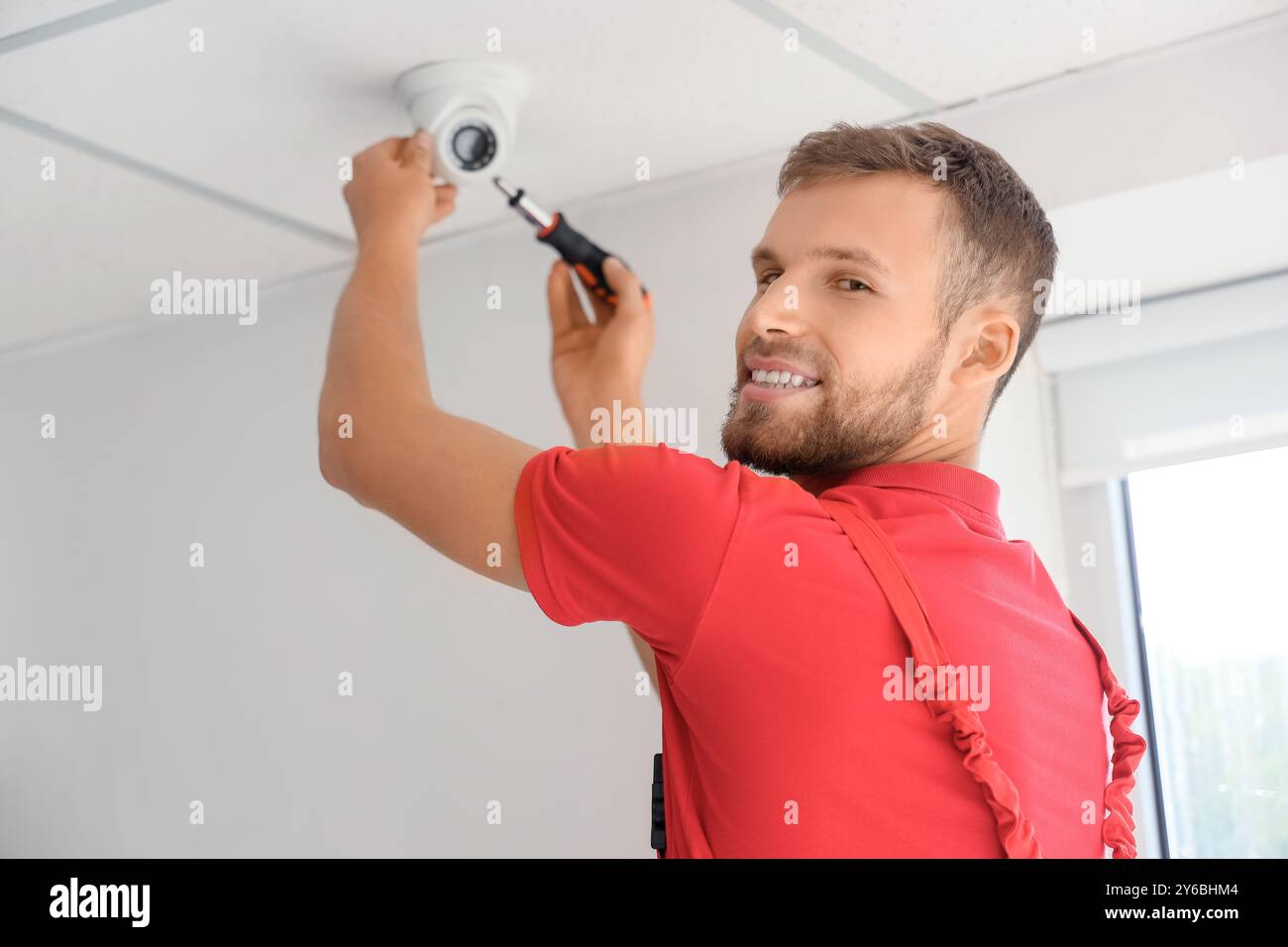 Male worker installing alarm system on ceiling in room Stock Photo - Alamy