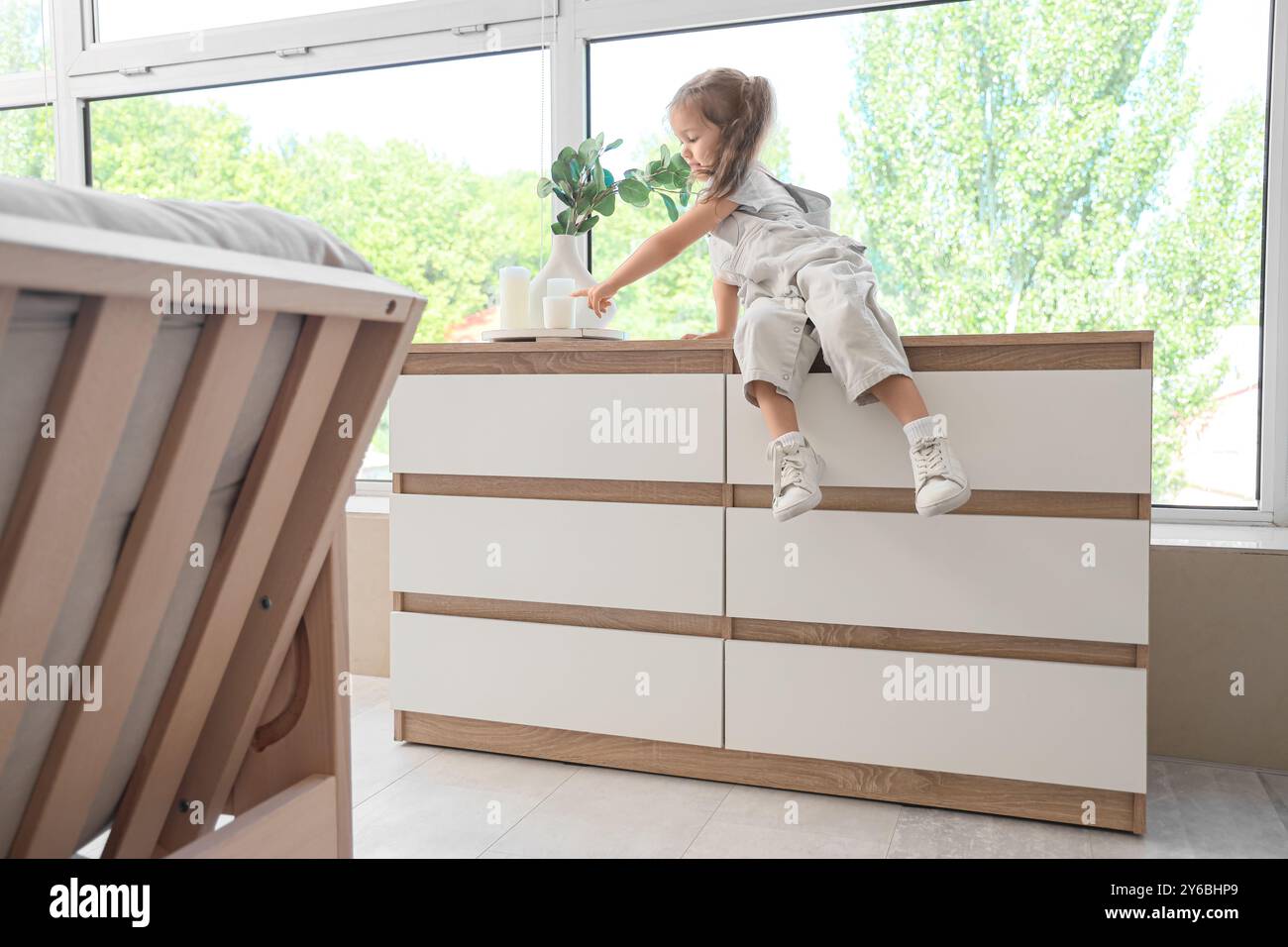 Cute little girl touching candles on high commode at home. Child in ...