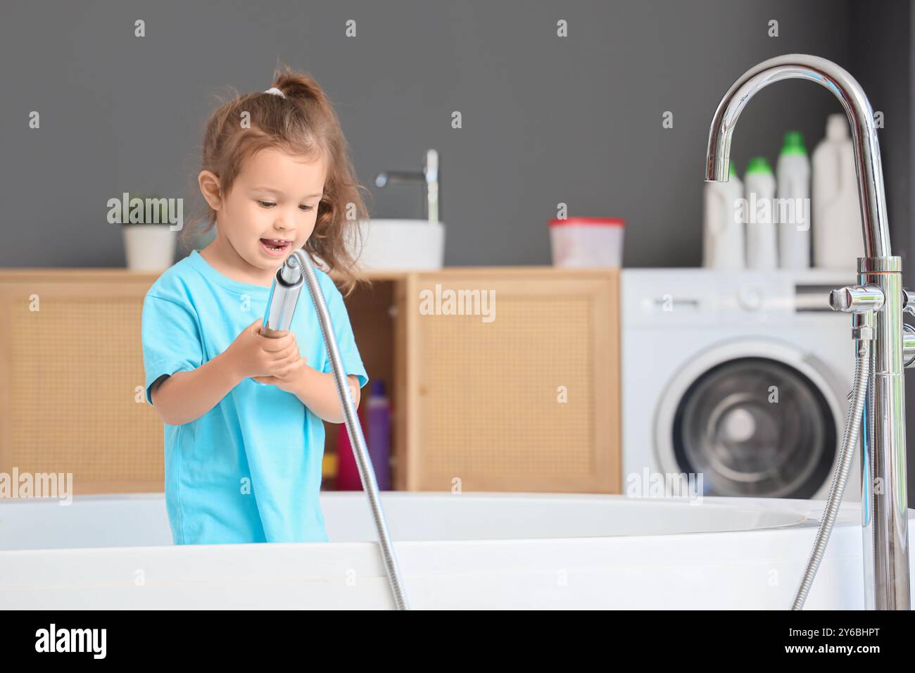 Cute little girl with shower head in bathtub. Child at risk Stock Photo ...
