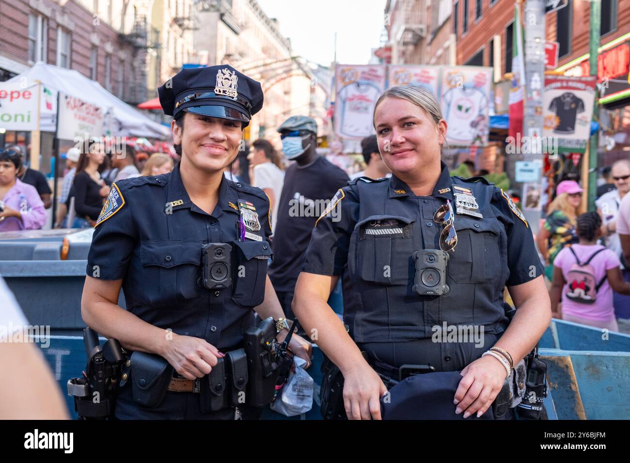 Two smiling NYPD officers pose for the camera in their uniforms, standing in the midst of the ...