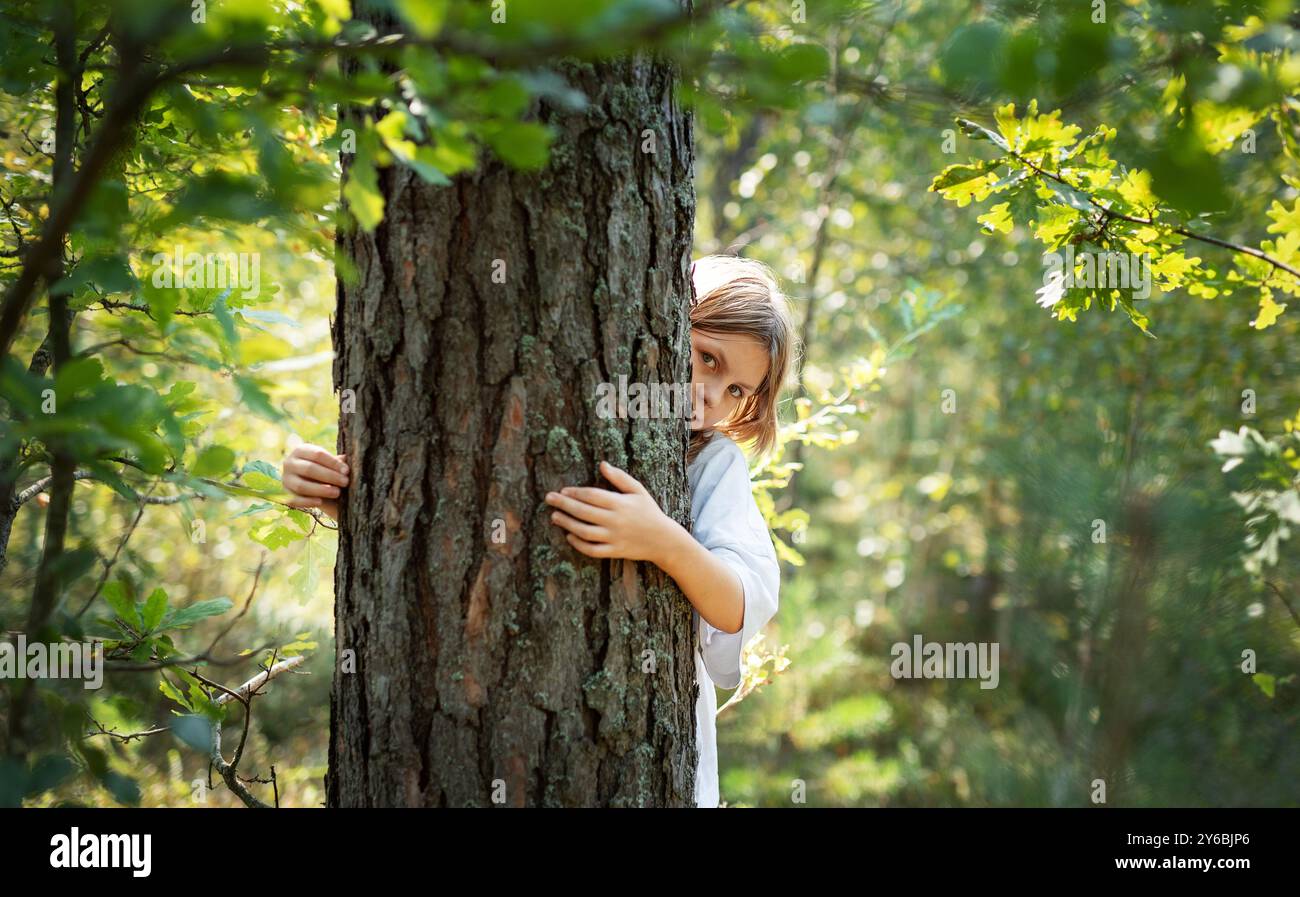 A teenage girl hugs a tree in the forest. Hugging and touching trees to ...