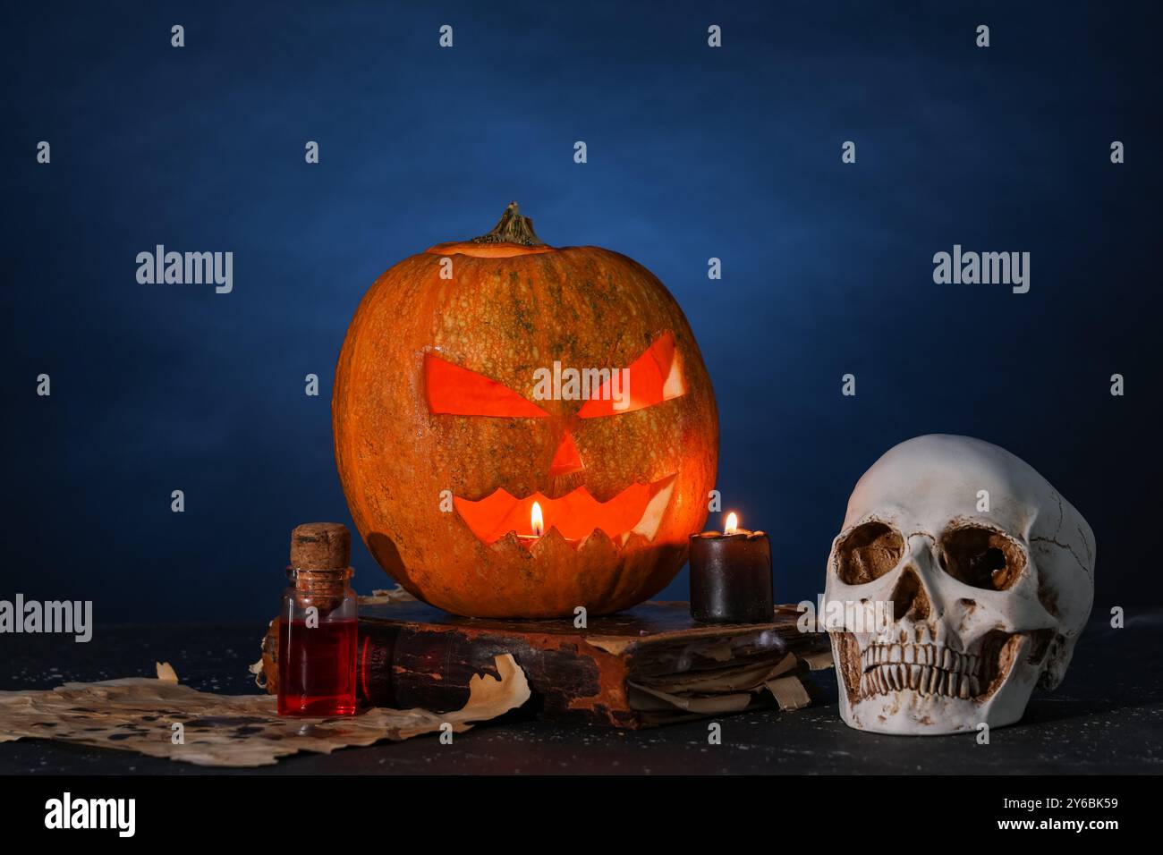 Halloween composition with jack-o-lantern, human skull, spell book and ...