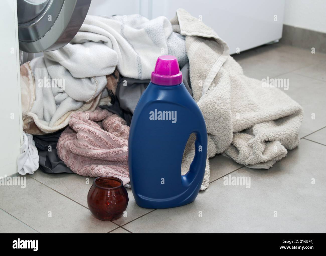 A blue bottle of liquid washing gel on grey floor near a washing ...