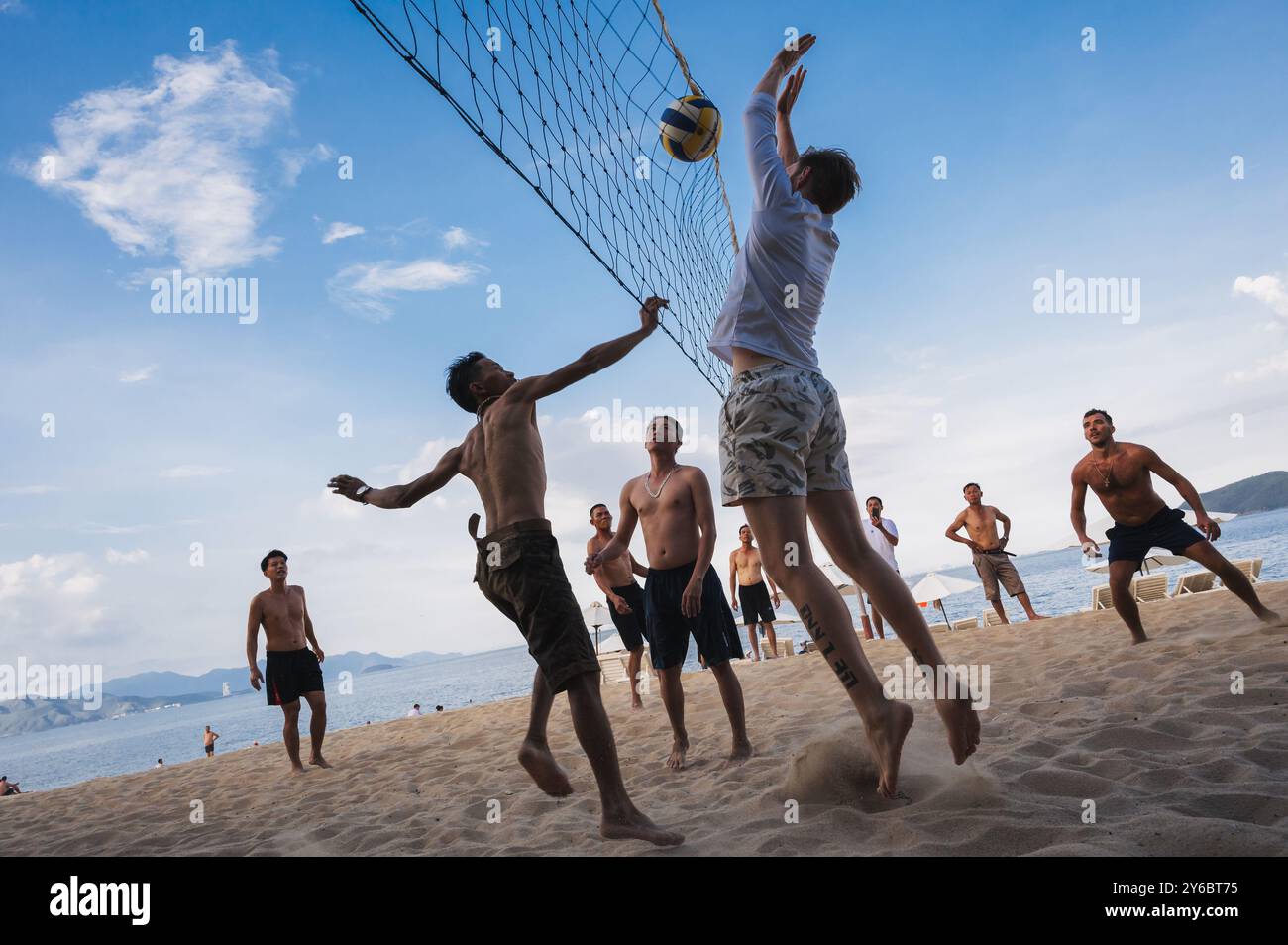 Teams with multinational players play beach volleyball by the sea in ...