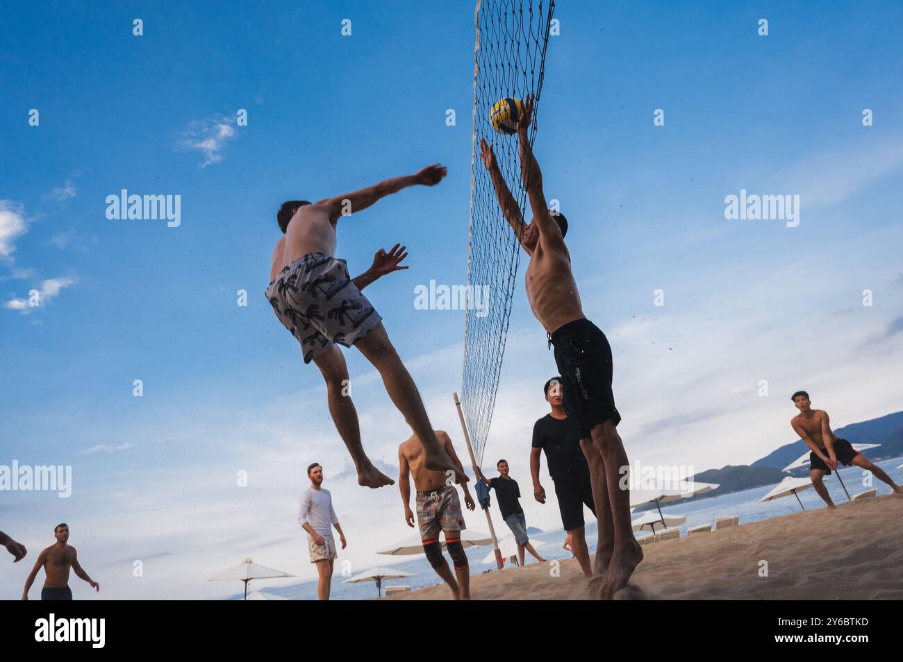 Teams with multinational players play beach volleyball by the sea in ...