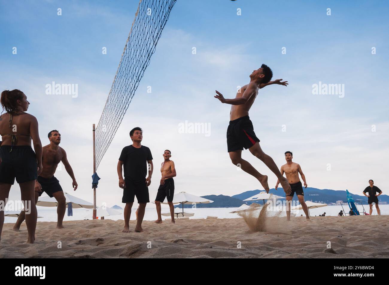 Teams with multinational players play beach volleyball by the sea in ...