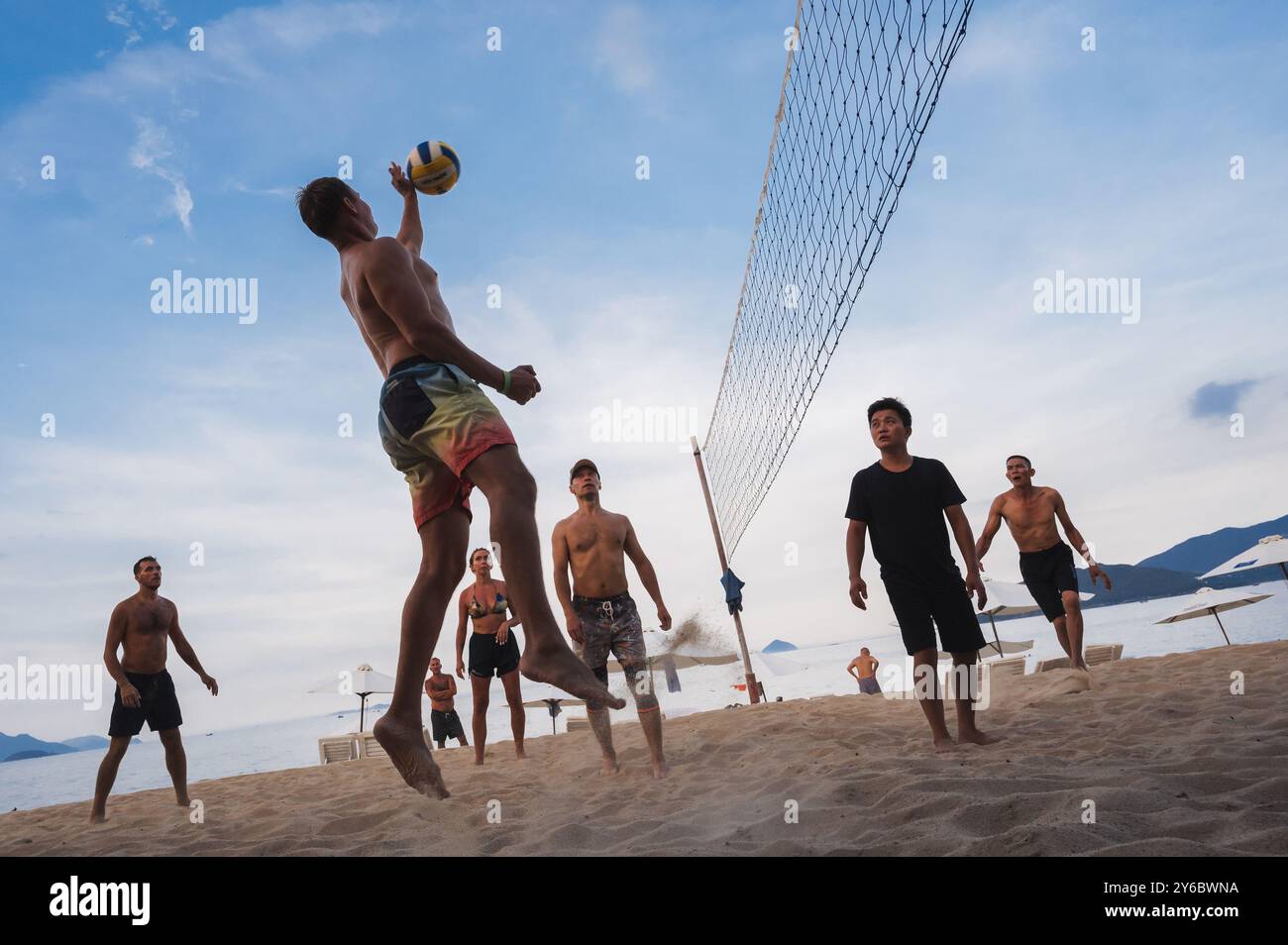Teams with multinational players play beach volleyball by the sea in ...